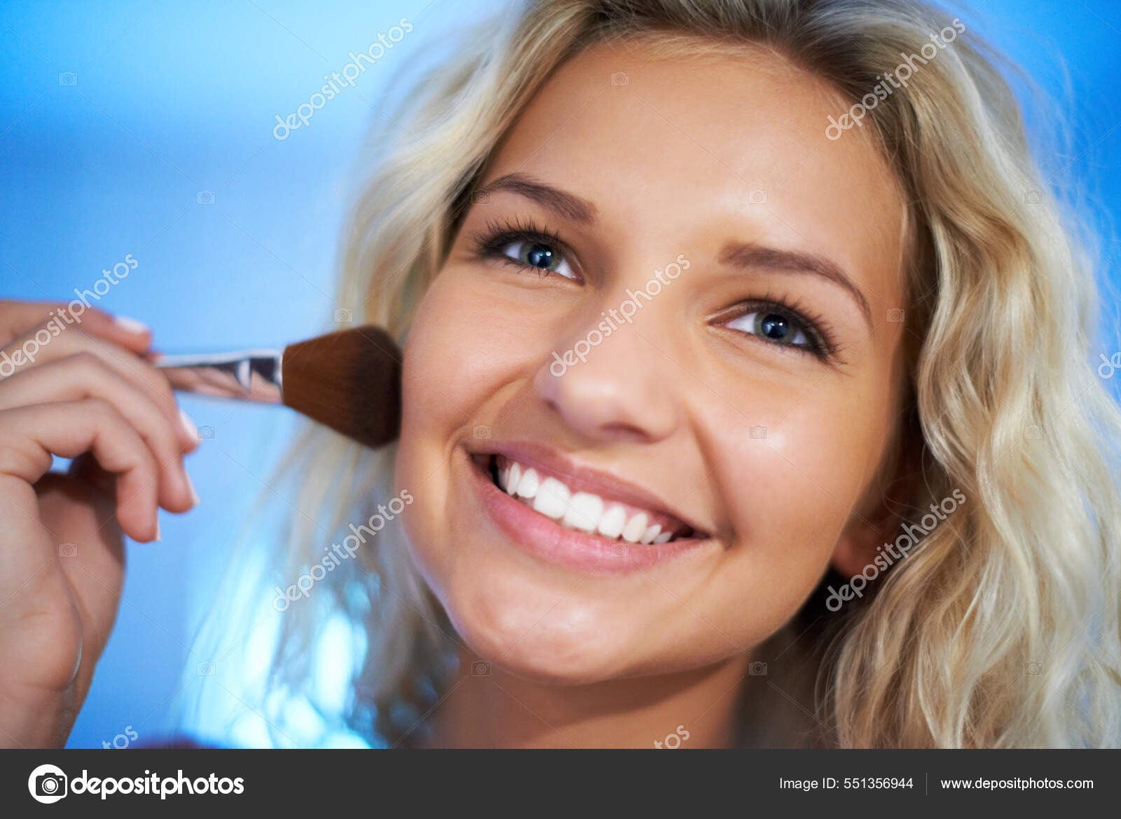 Adding a touch of pink. Pretty young woman putting on some blusher ...