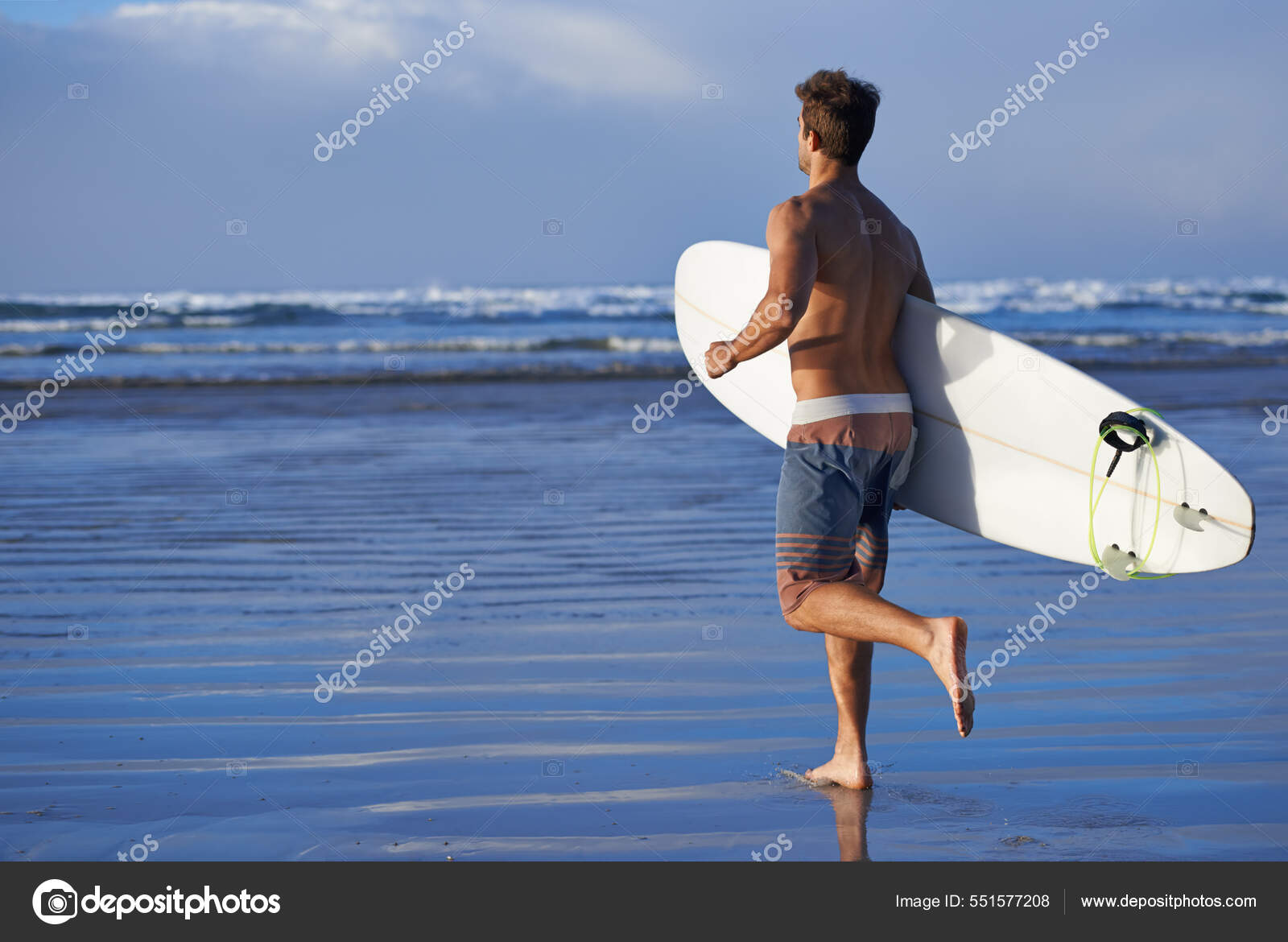 Chasing waves. A handsome young surfer at the beach craving a good wave ...