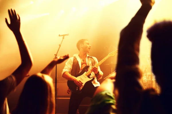 Cropped shot of a guitarist on stage surrounded by adoring fans. This ...