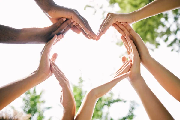 Multiethnic hands making a heart shape outside in nature. Closeup of a ...