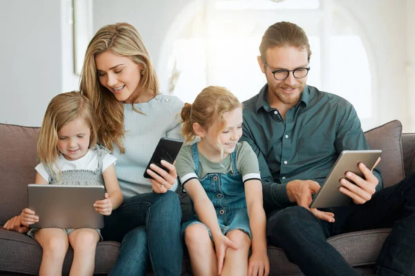 Shot of a young family sitting on the sofa together and bonding while ...