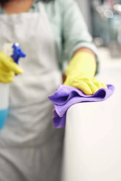 a woman using a spray bottle and cloth while cleaning a counter ...
