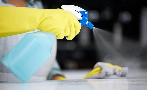 a woman using a spray bottle and cloth while cleaning a counter ...