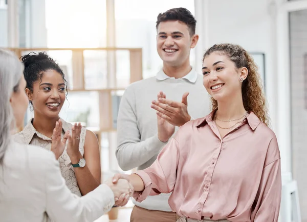 Happy businesswomen shaking hands while their colleagues clap hands in ...