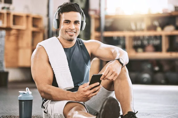 Portrait of happy trainer in the gym. Strong, fit man listening to ...