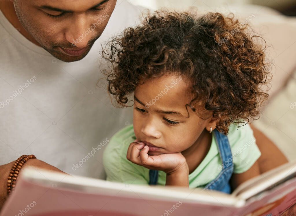 Story time with dad. a young father reading a book with his daughter at home 2024