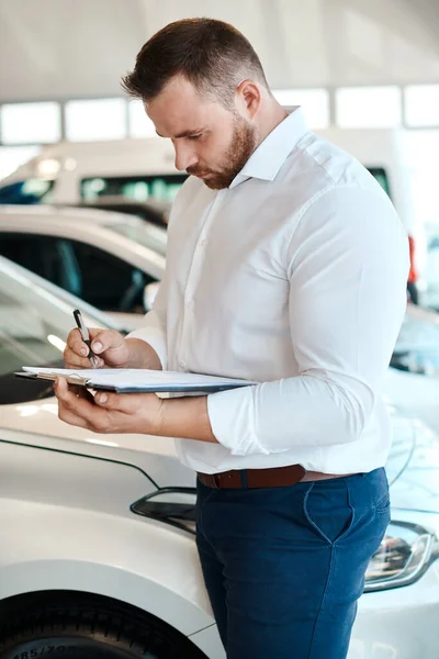 Sign on the dotted line. a car salesman writing on a clipboard - Stock ...