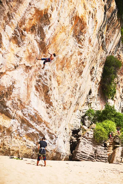 They share an adventurous spirit. two young people rock climbing on a ...
