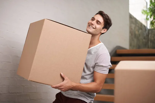 Moving house is exciting. A happy young man moving packed cardboard ...