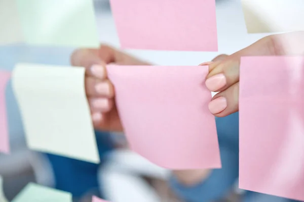 Closeup of unknown business woman using sticky notes on a transparent ...