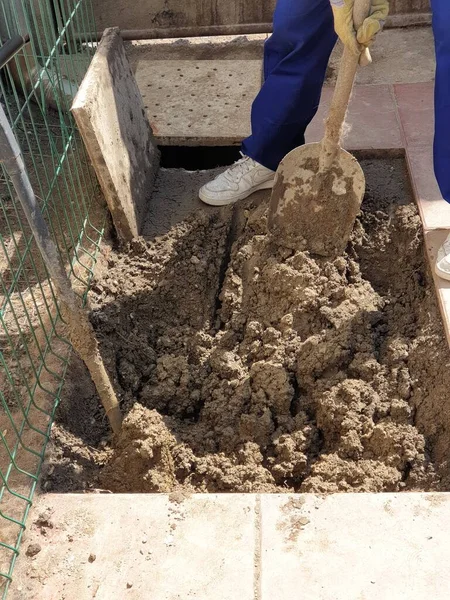 a worker digs a hole in the ground to repair a broken water pipe ...