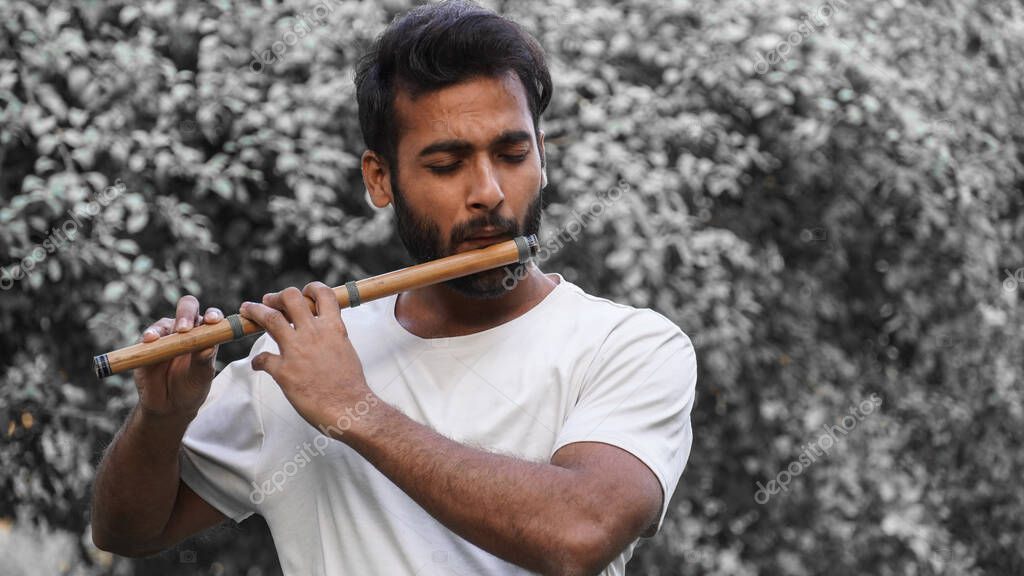 Reproductor de Bansuri tocando música bajo el sol en Park - Indian Flute Player 2024