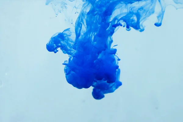 Colors dropped into liquid in motion. Ink swirling in water. Blue ink ...