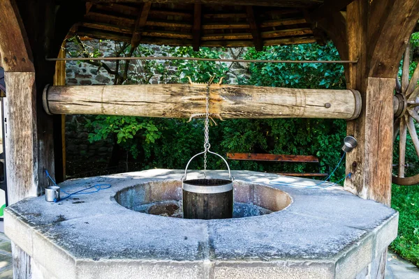 Pozo arcaico con polea y cubo de madera. 2023