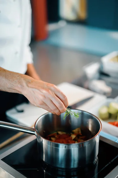 Professional restaurant kitchen, close-up: the chef throws greens into ...