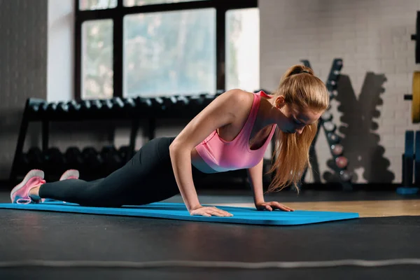Athletic woman is engaged in training push-ups in gym. chest and arm ...