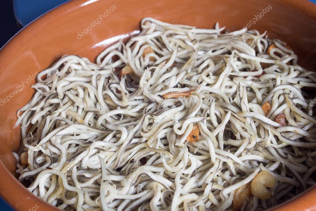 Primer plano de anguilas con ajo en un tazón de barro rústico listo ...