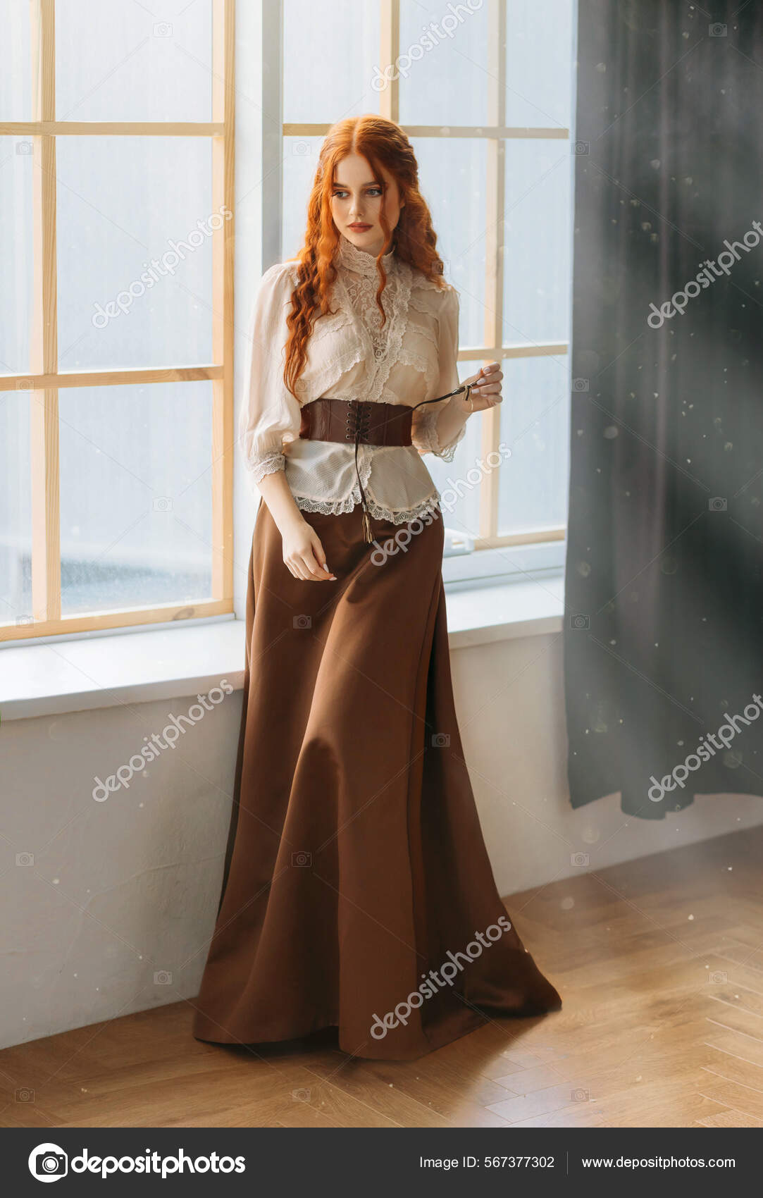 Red Haired Woman In Vintage Dress Stands At Large Classic Window
