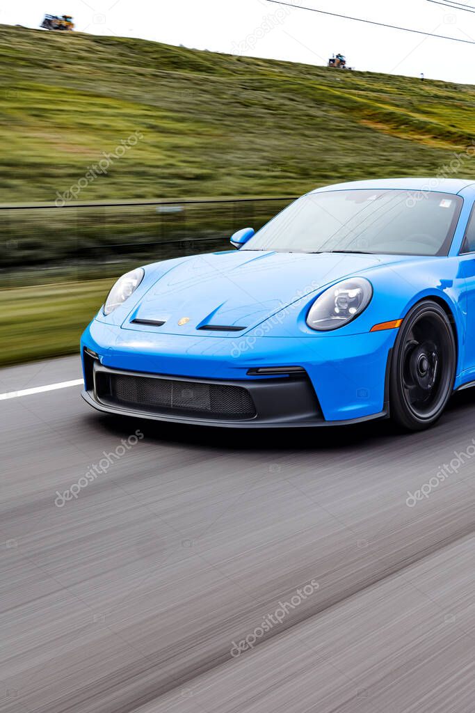Un disparo vertical de un Porsche 911 GT3 azul deportivo en movimiento 2023