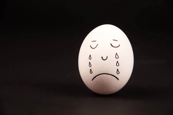 A closeup of a painted egg with a funny face on a black background ...