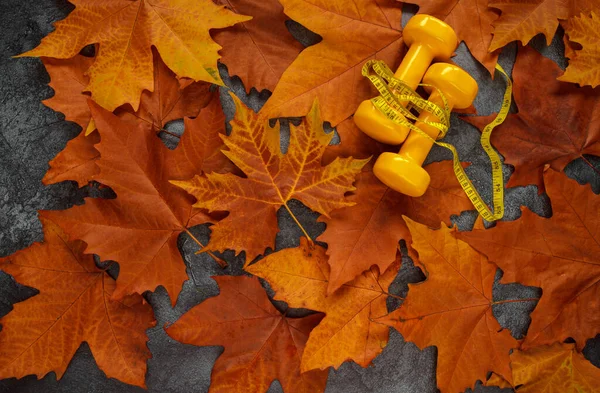 Two yellow dumbbells with tape measure (or measuring tape) on autumn ...