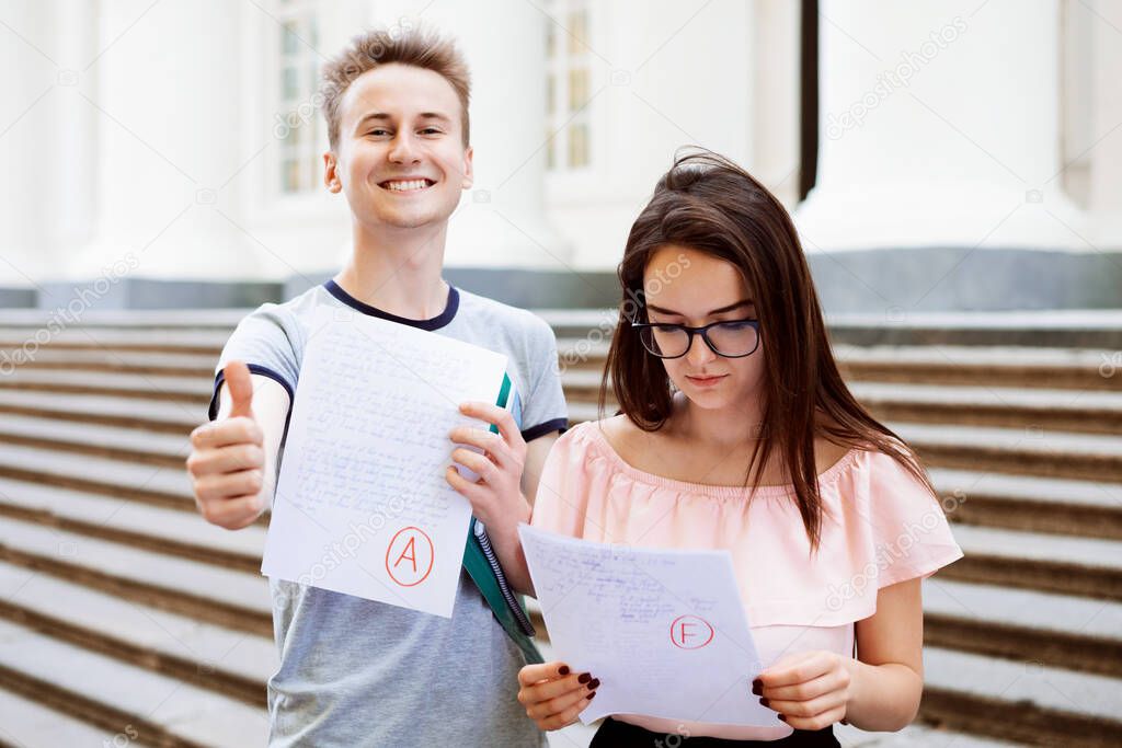 Retrato de vista frontal de dos estudiantes que muestran exámenes ...
