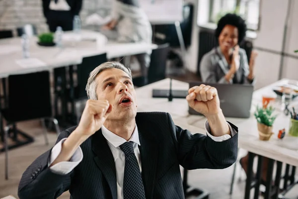 High angle view of businessman looking up and punching the air while ...