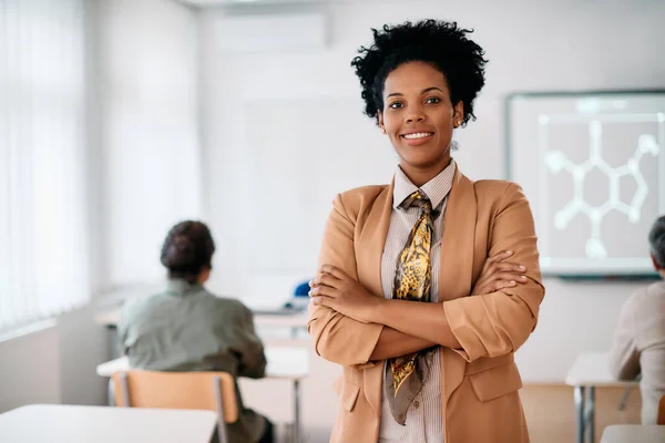 Happy black female professor standing with arms crossed in the ...