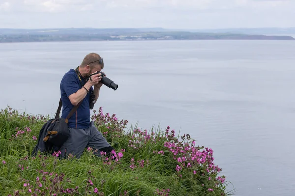 Fotógrafo tomando fotos de flores en Bempton Cliffs, una reserva ...