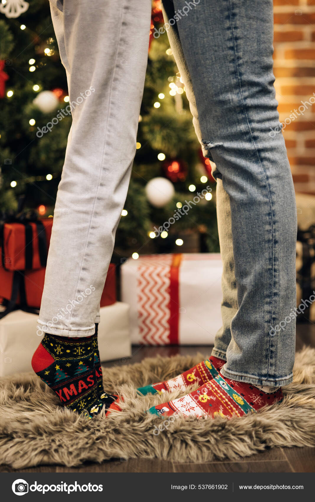 Two pairs of foot, dressed in Xmas soks. Atmosphere of Christmas. Legs ...