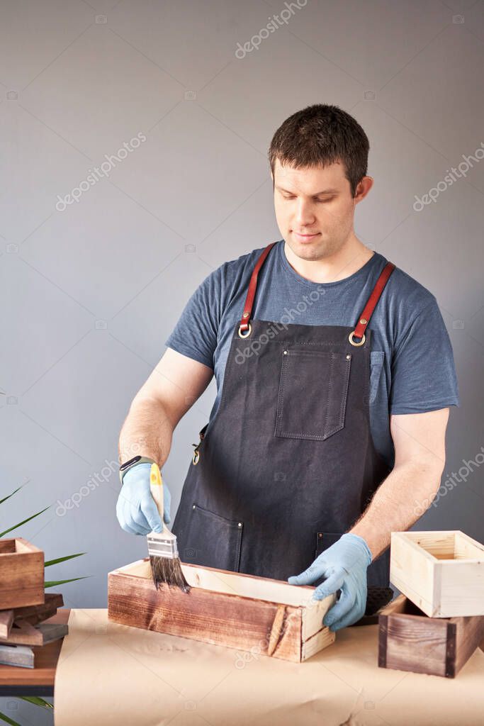 Hombre carpintero barnizado caja de madera con cepillo en su pequeño ...