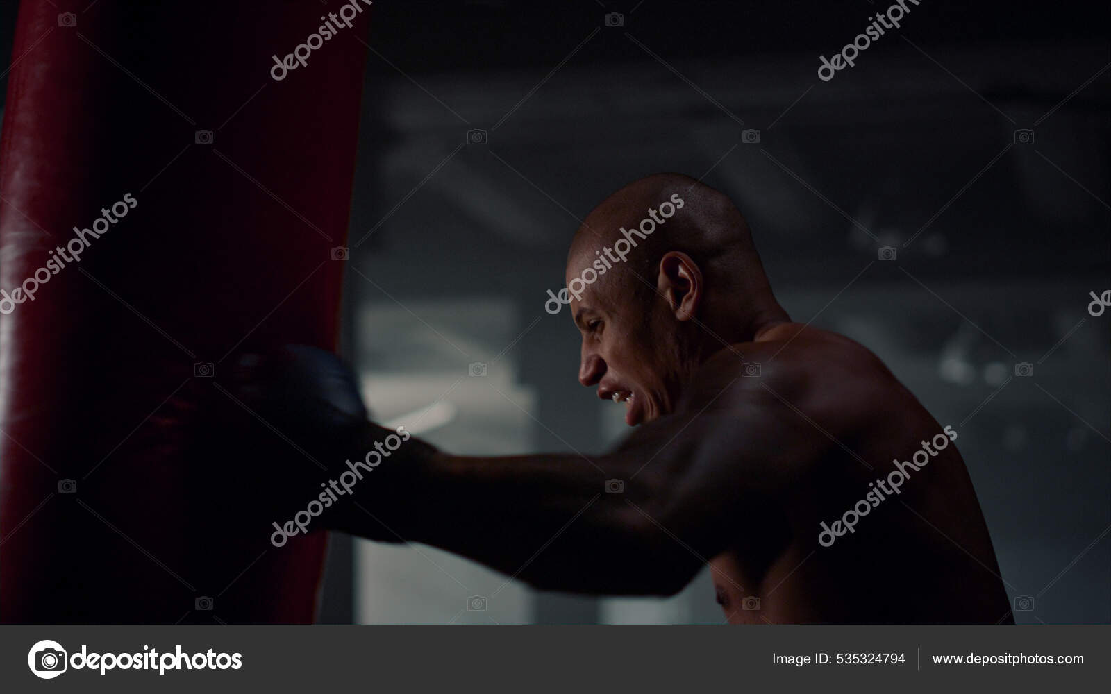 Angry man hitting punching bag. Sportsman training punches in sport ...