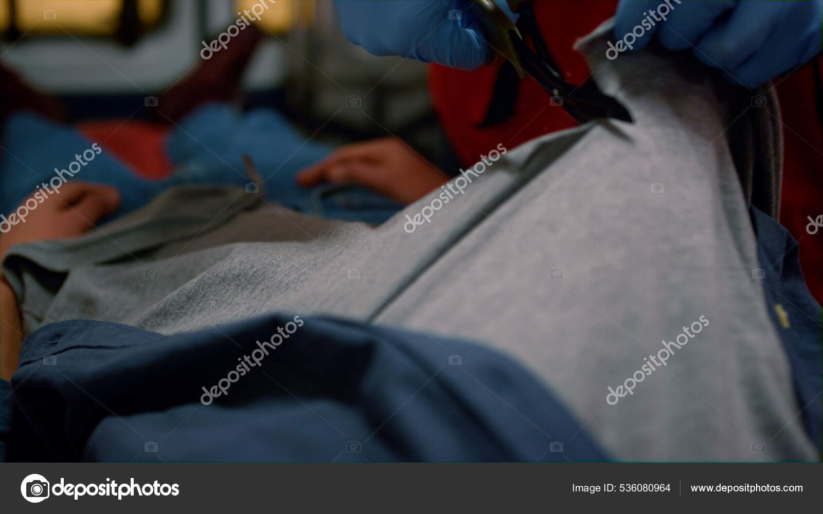 Paramedic hands cutting patient clothes with scissors to provide ...