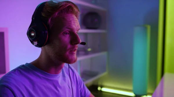 Cyber player talking headset communicating with team in neon room close ...