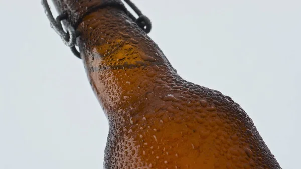 Clear condensate drops flowing down glass bottle with fresh cold beer ...