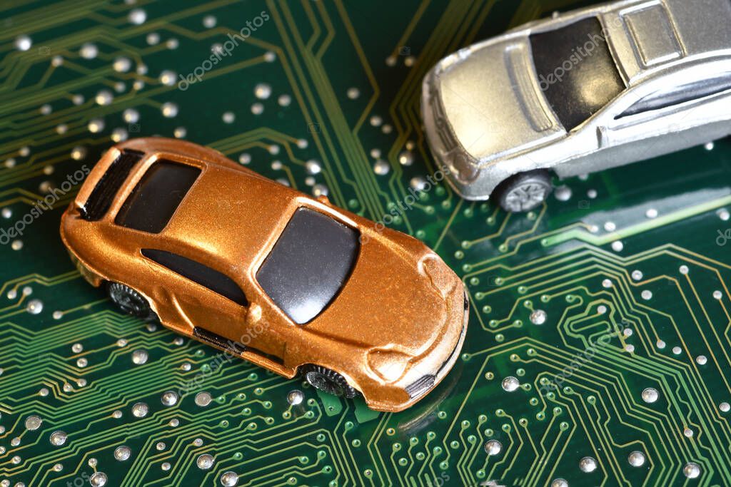 Coches de juguete en una placa electrónica con circuitos integrados. La escasez de microchips y ...