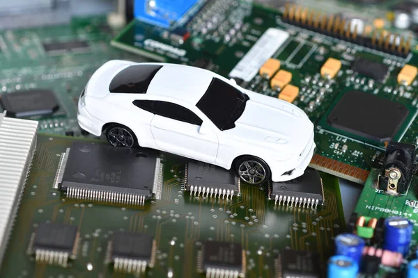 Coche de juguete en tablero electrónico y microchip. Imagen conceptual para la escasez de ...