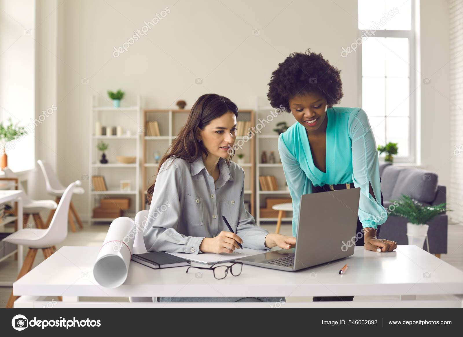 Two young architects or interior designers working on laptop computer ...
