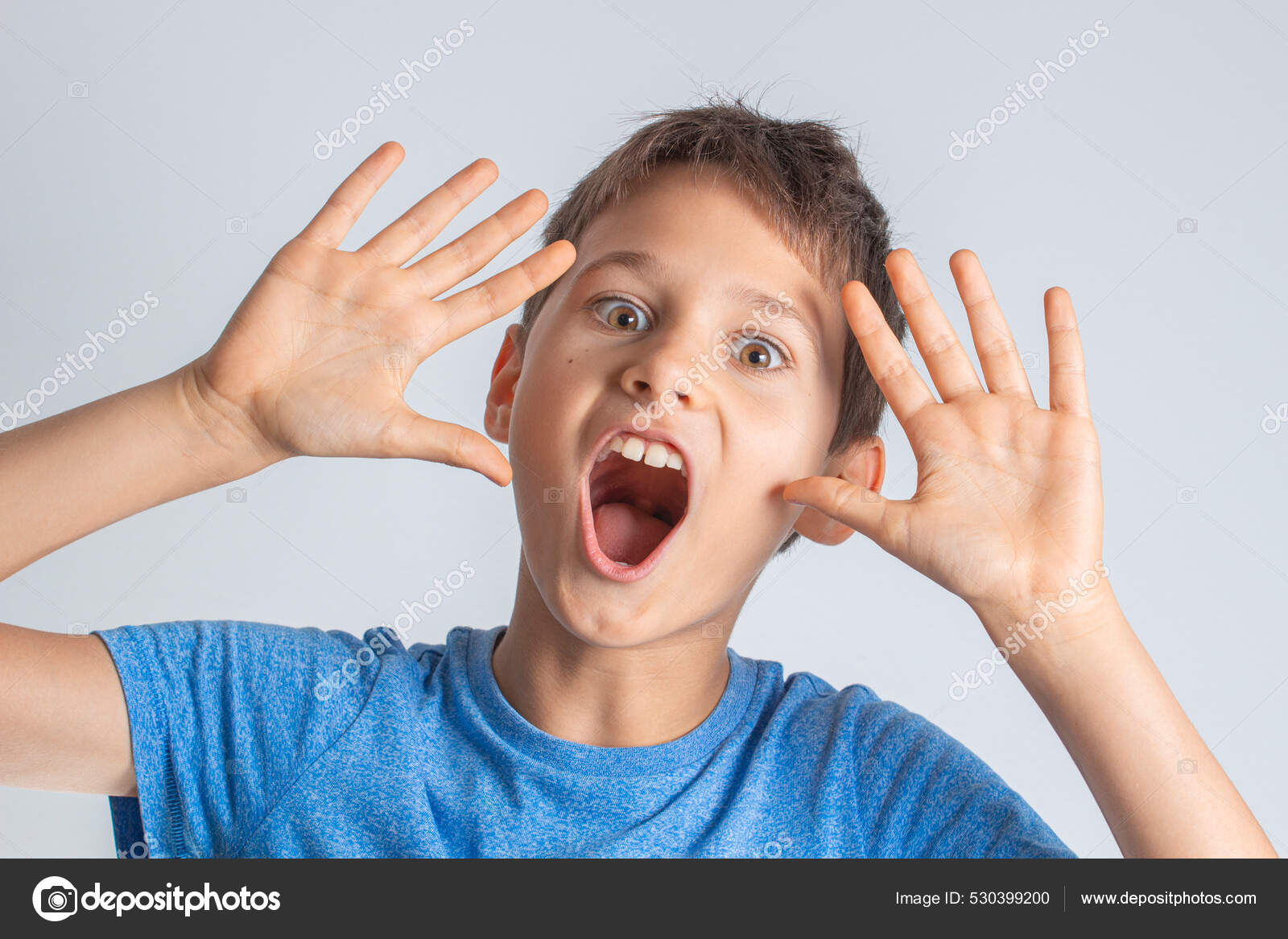 Portrait of shocked surprised boy with opening mouth and rised hands ...