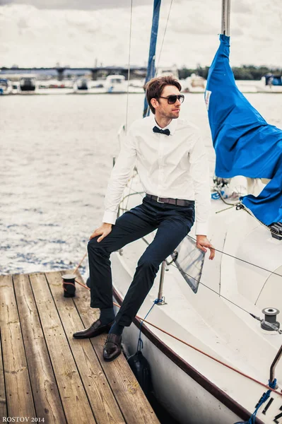 Handsome man, a serious captain in a white shirt near the yacht ...