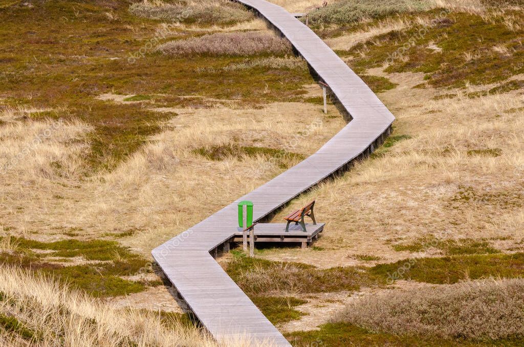Rest area with a bench and a green rubbish bin on a path through a dune ...