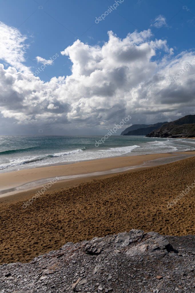 una costa rocosa del océano con montañas y una hermosa playa de arena ...